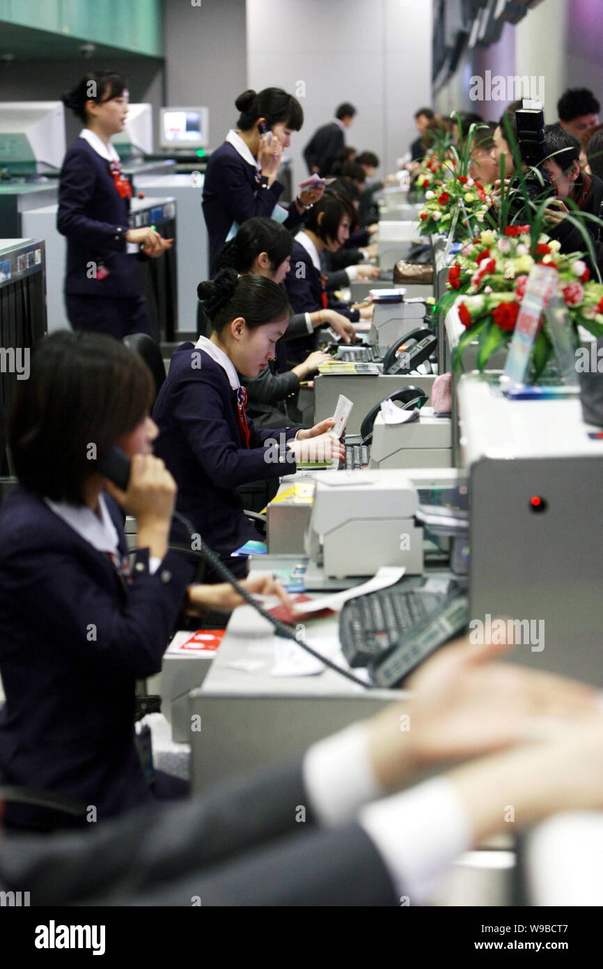 Chinese airport staff work on boarding tickets for passengers in the ...