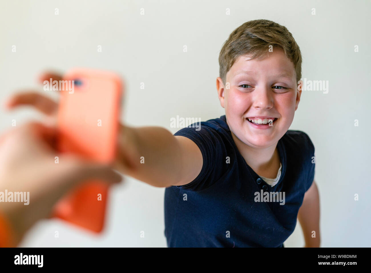 Blond emotional kid reaches his hand to the mobile phone. Phone ...