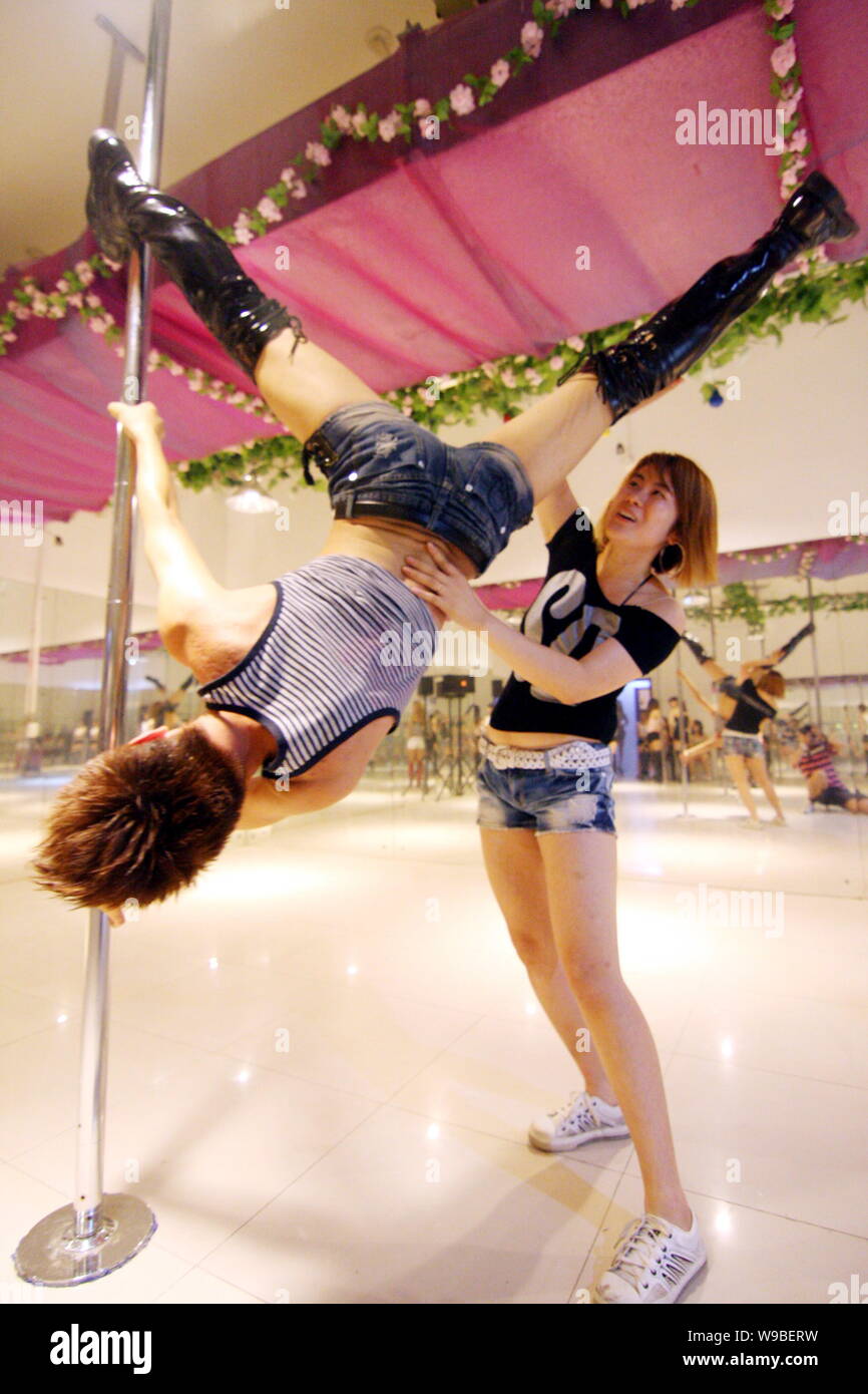 A Chinese teacher helps a young man learn pole dancing at a dance ...