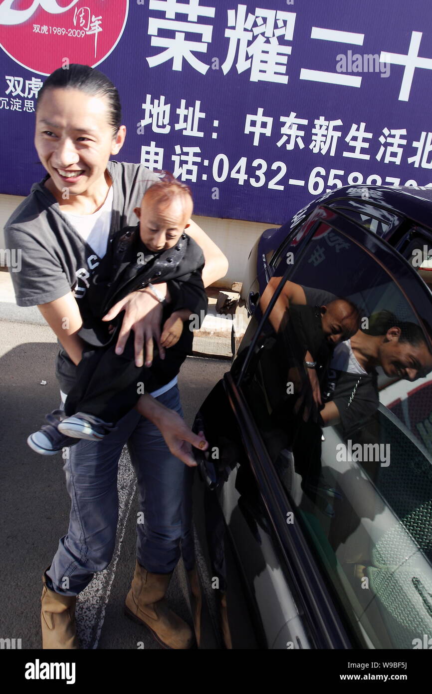 --FILE-- The worlds shortest man He Pingping (R) is held by a man in ...