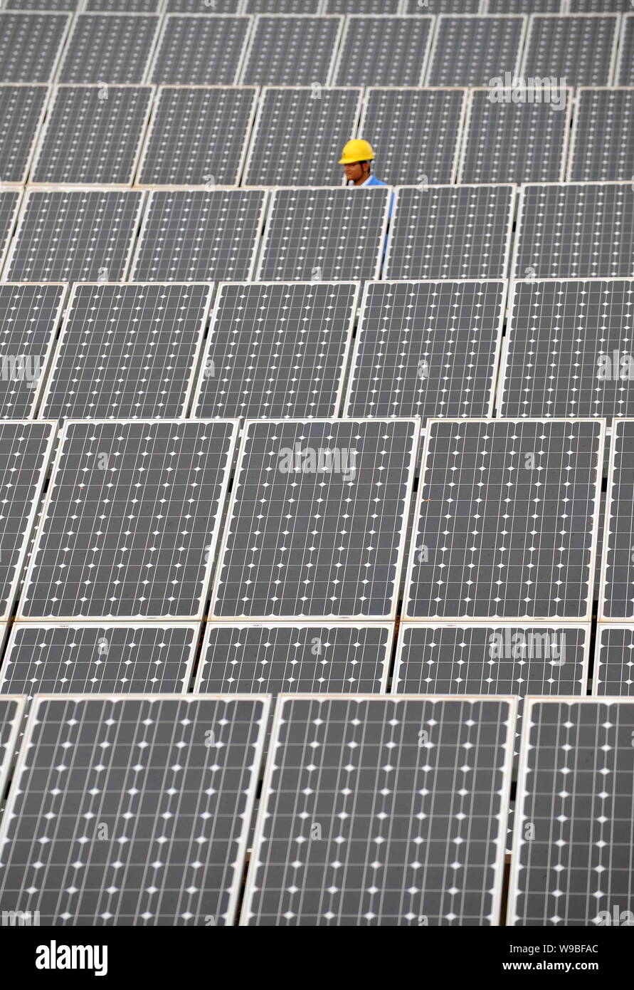 A Chinese electrician checks arrays of photovoltaic panels at the ...