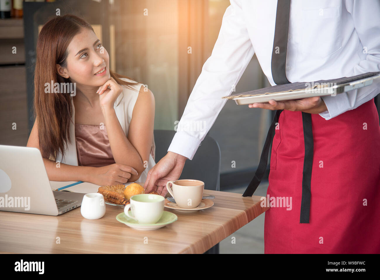 Beautiful business woman smiling looking at handsome waiter while ...