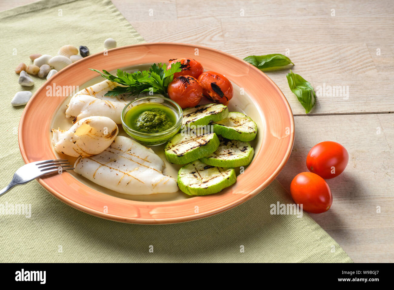 Grilled squid with squash decorated with tomatoes and sea shells Stock ...