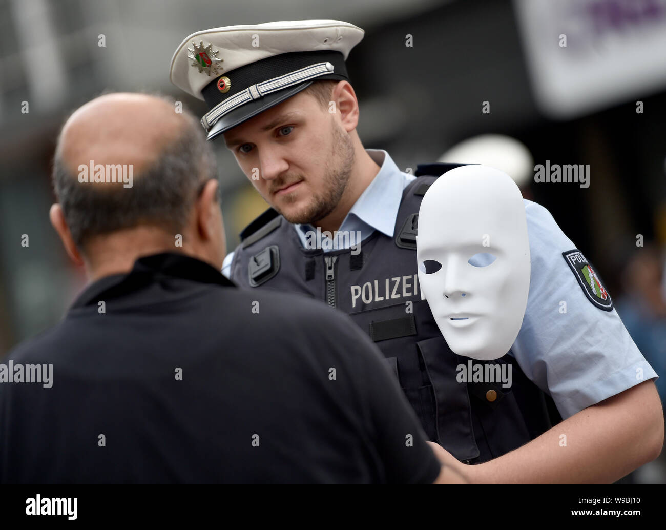 Essen, Germany. 13th Aug, 2019. A policeman wears a white mask on his ...