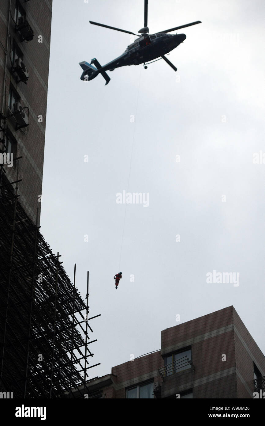 A Chinese rescuer tries to descend from a helicopter to rescue the ...