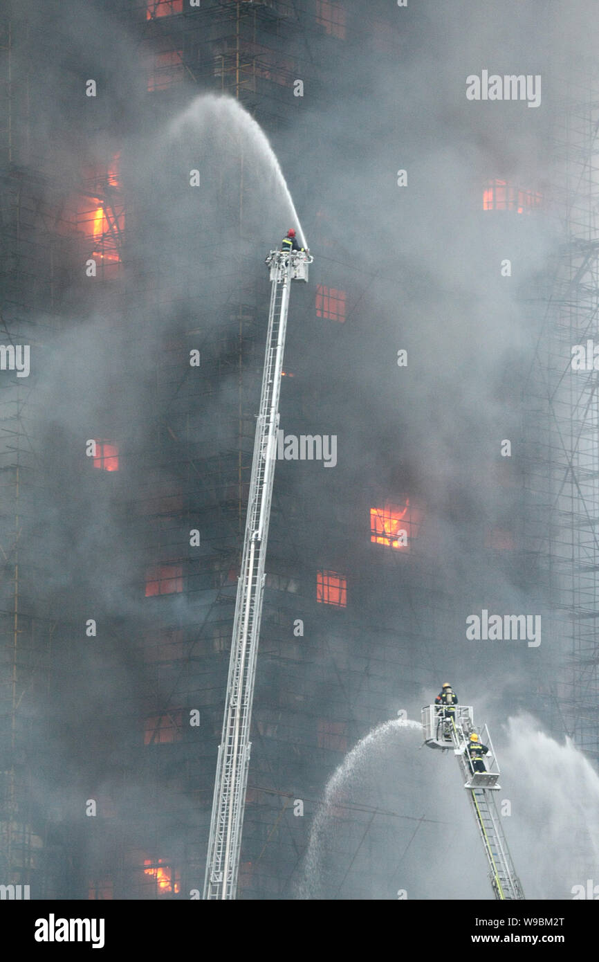 Chinese firefighters hose water to extinguish the fire in a residential ...
