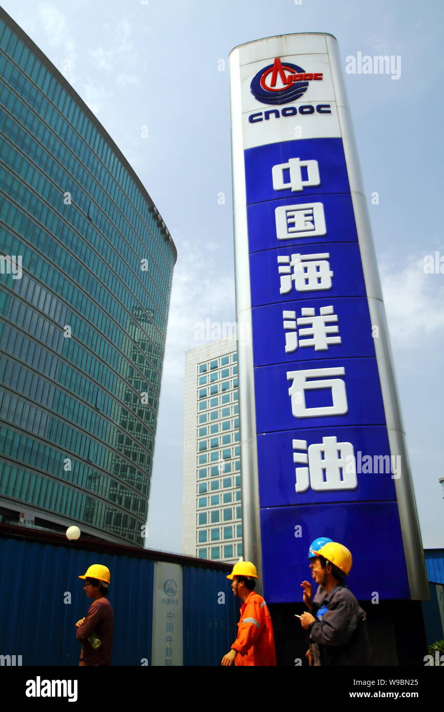 Chinese construction workers walk past the headquarters of CNOOC (China ...