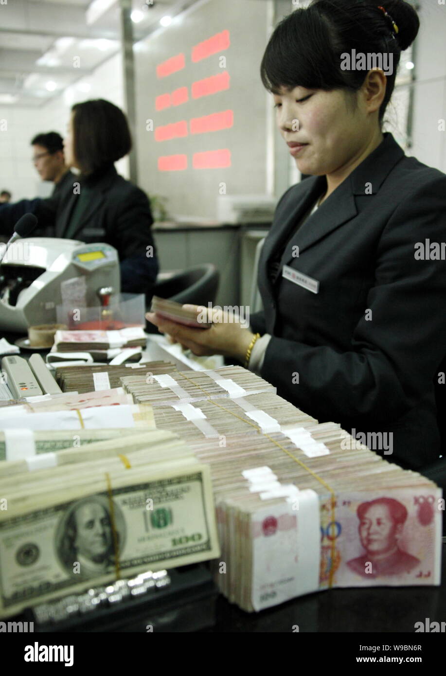 --FILE--A Chinese bank clerk counts RMB yuan and US dollar banknotes at ...