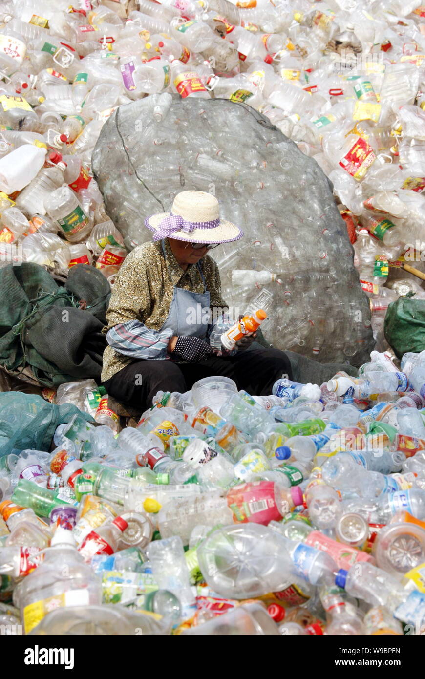 --FILE--A Chinese worker cleans up waste plastic bottles at a recycling ...