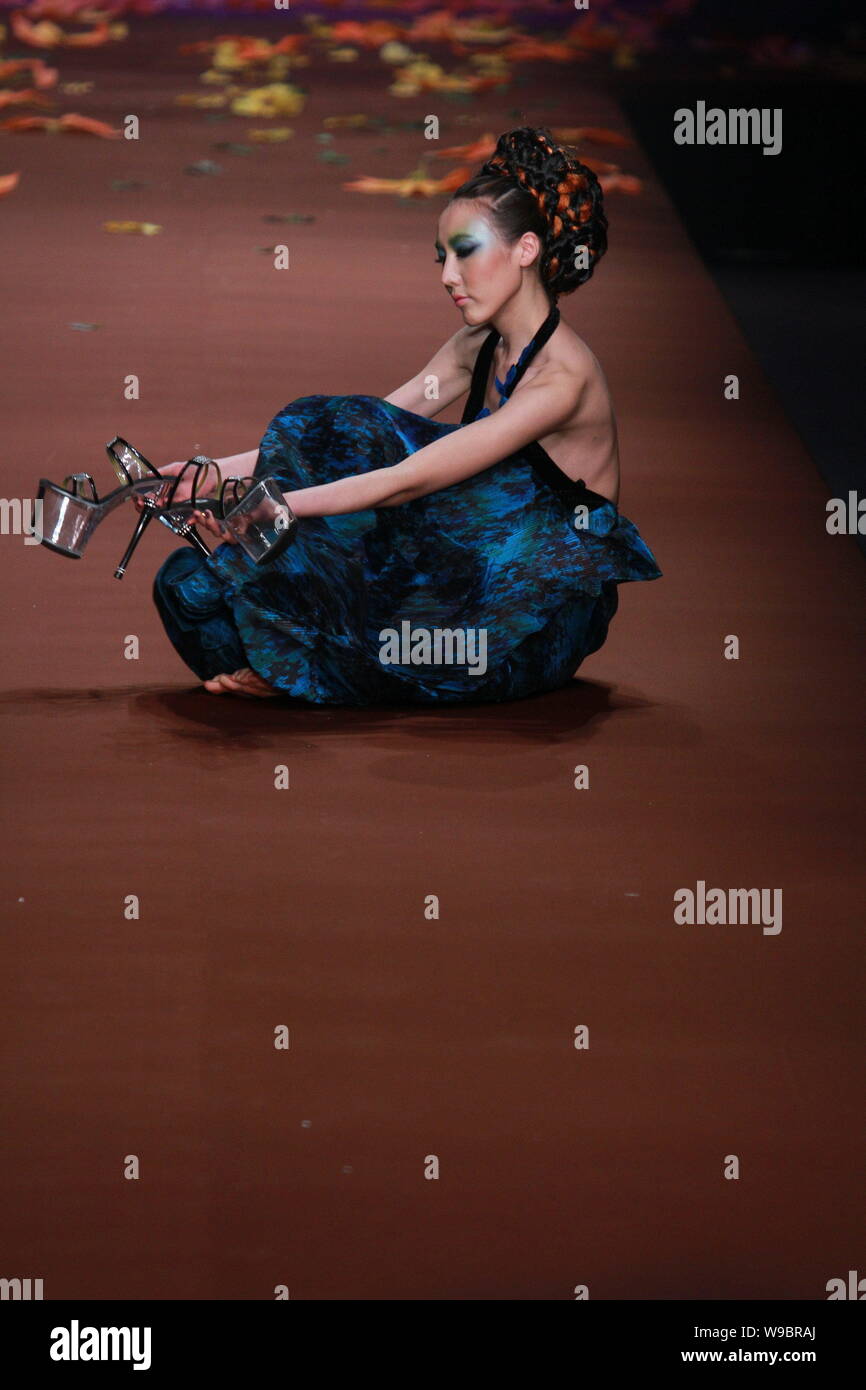 A model takes off her high-heel shoes after falling down at the ...