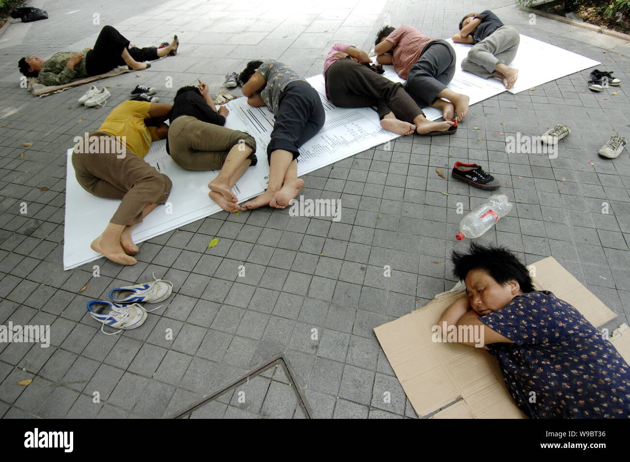 Chinese migrant workers sleep on the ground in a shade in a heat wave ...