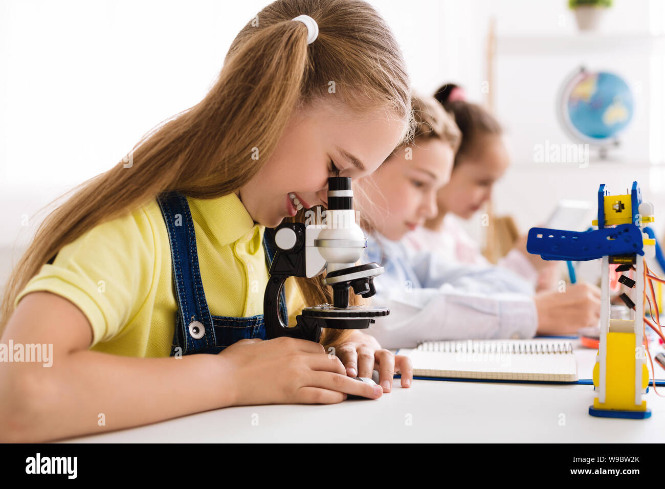 Stem education. Little girl looking at microscope Stock Photo - Alamy