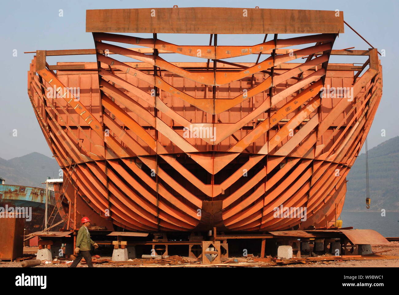 --FILE--A Chinese worker walks past a ship being built at the Yuxin ...