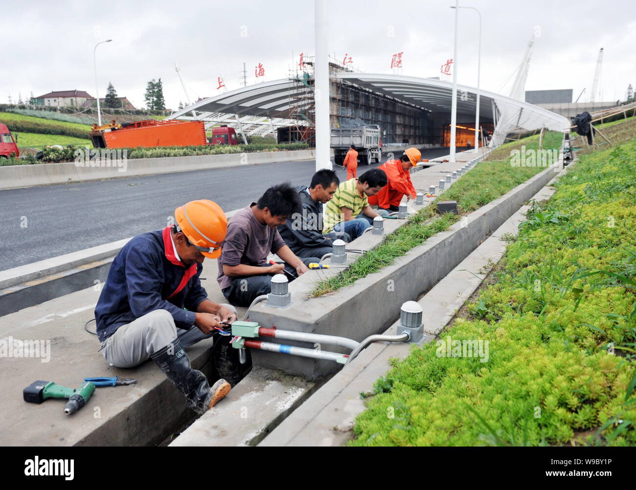 Chinese workers install signal lights at one entrance of the tunnel of ...