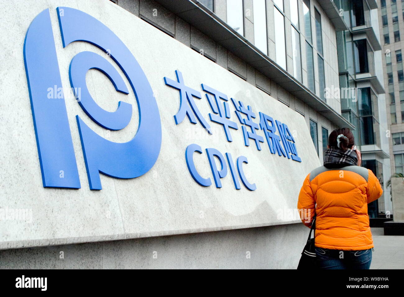 --FILE--A young Chinese woman walks past a signboard of CPIC (China ...