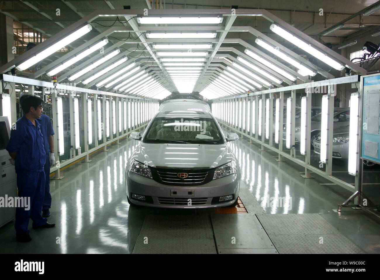 Chinese factory workers look at Geely Emgrand EC718 cars at an auto ...