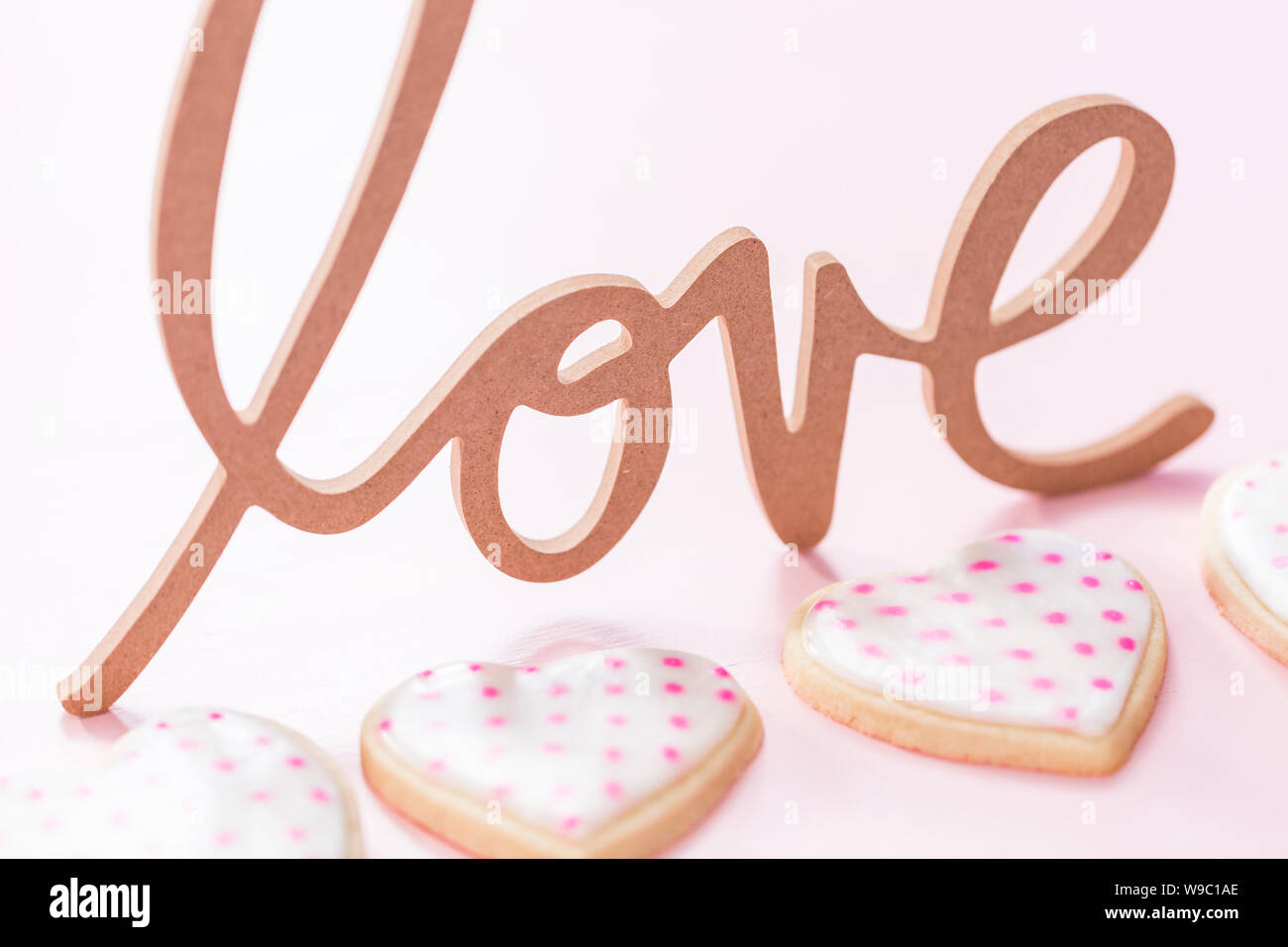 LOVE sign with heart shaped sugar cookies on a pink background Stock ...