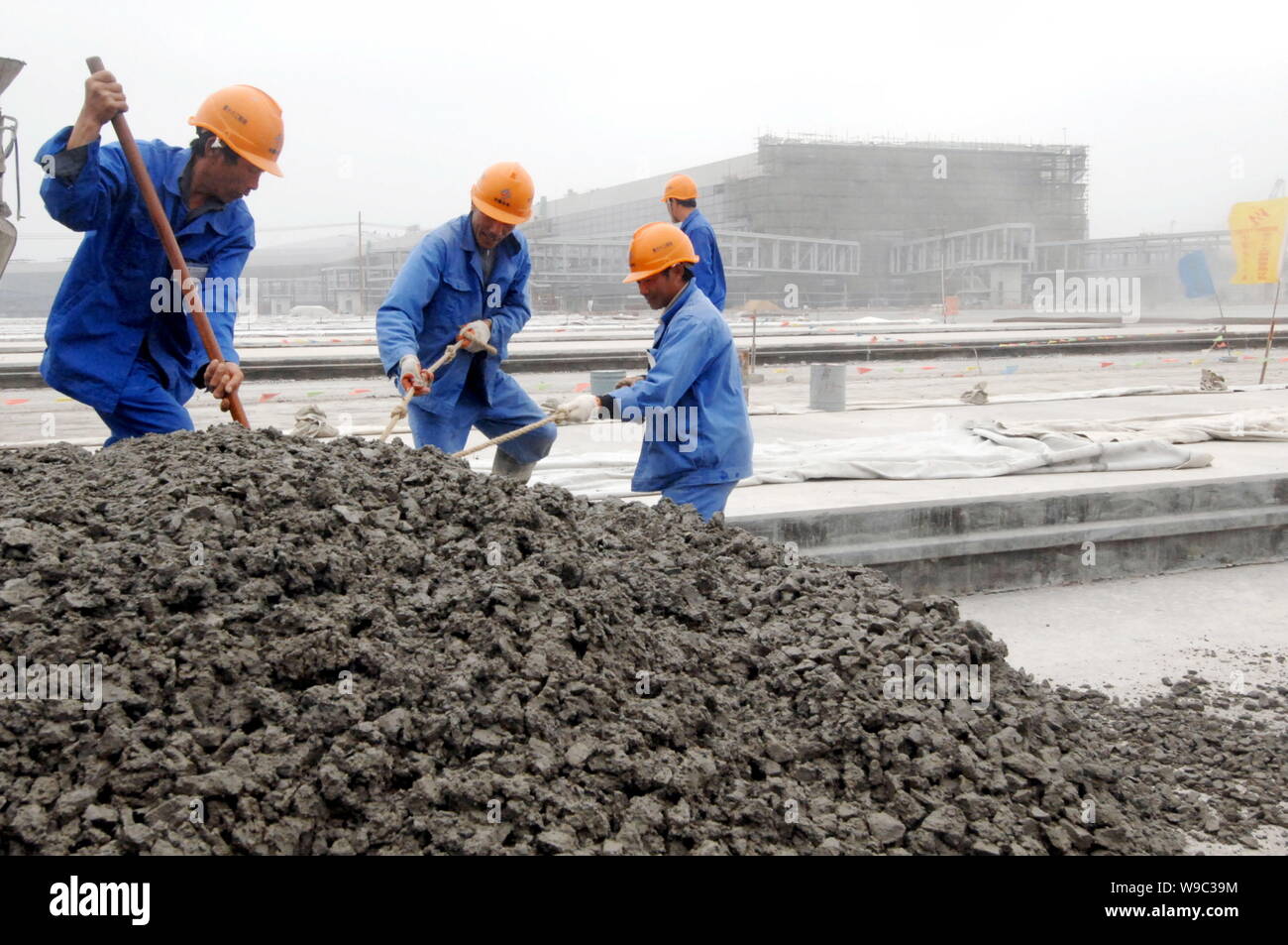--FILE--Chinese workers pave concrete at the construction site of the ...