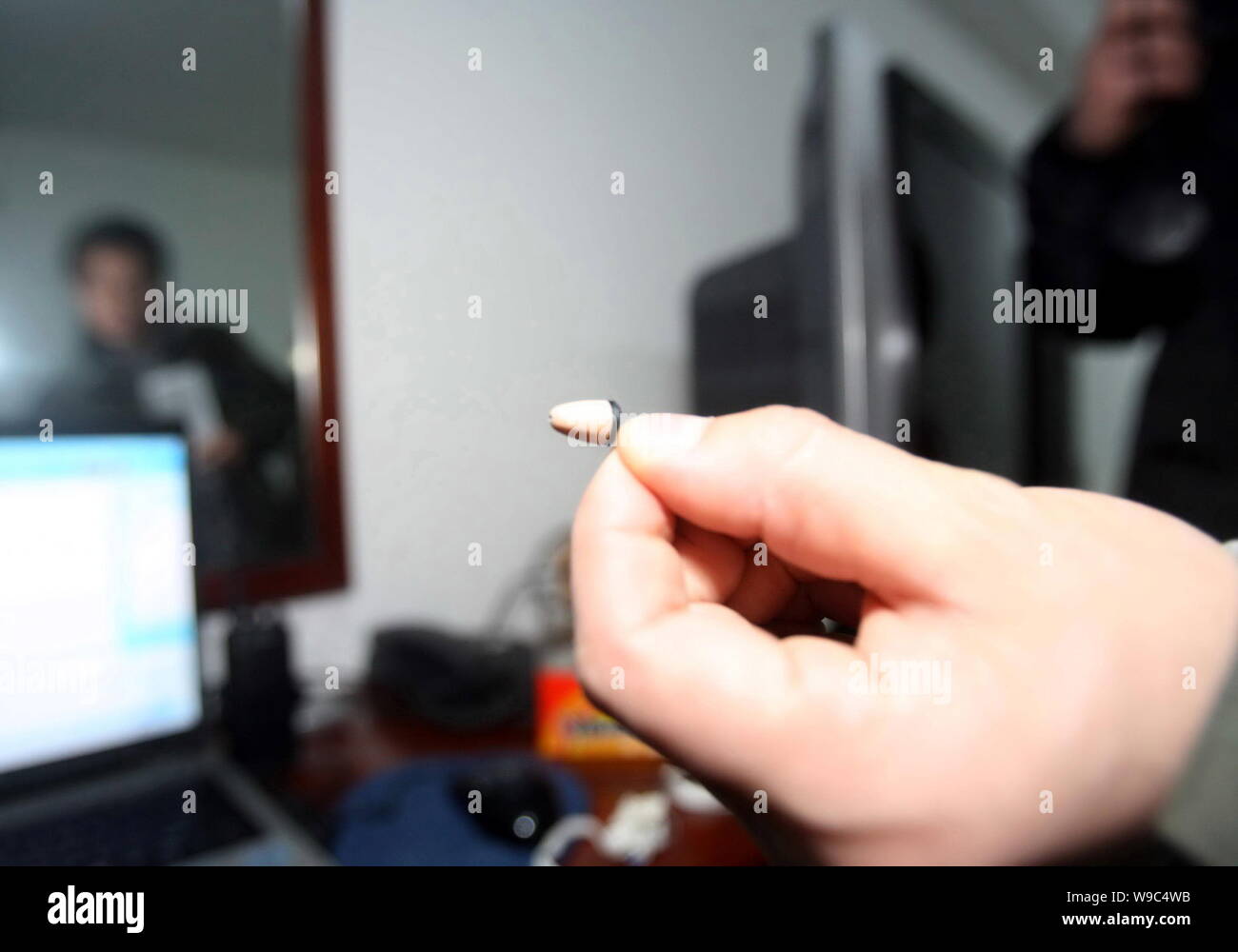 A Chinese radio administration officer shows a mini earphone used for ...