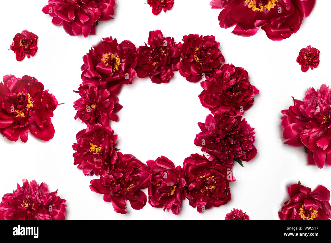 Frame of peony flowers, branches, and petals with space for text on ...