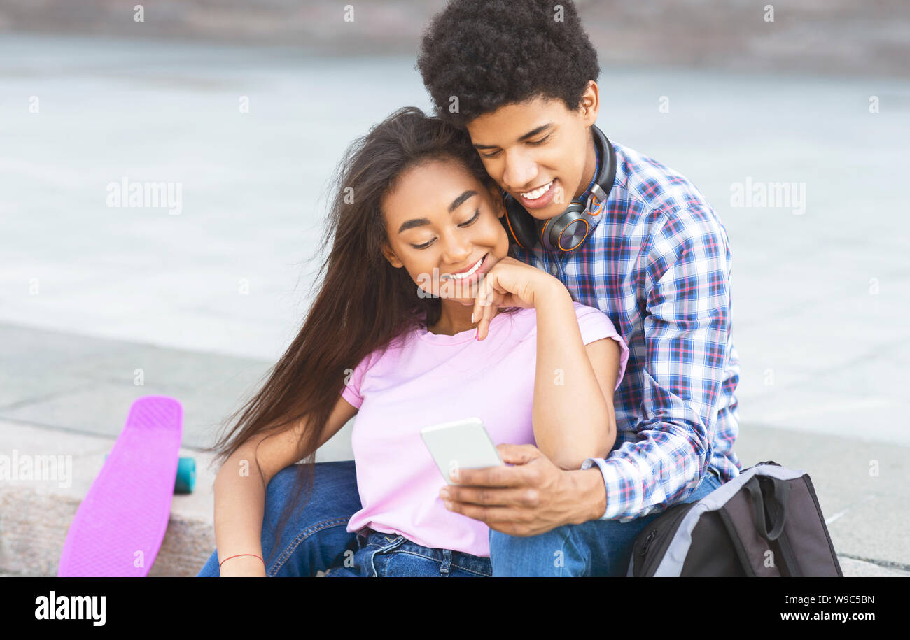 Smiling students scrolling photos in smartphone together sitting ...