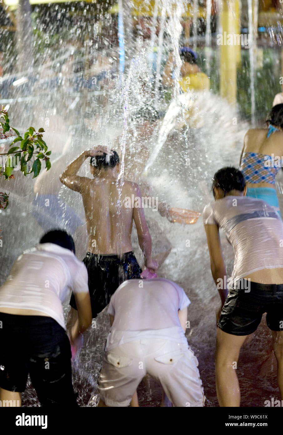 Chinese tourists and local citizens splash water during a water ...