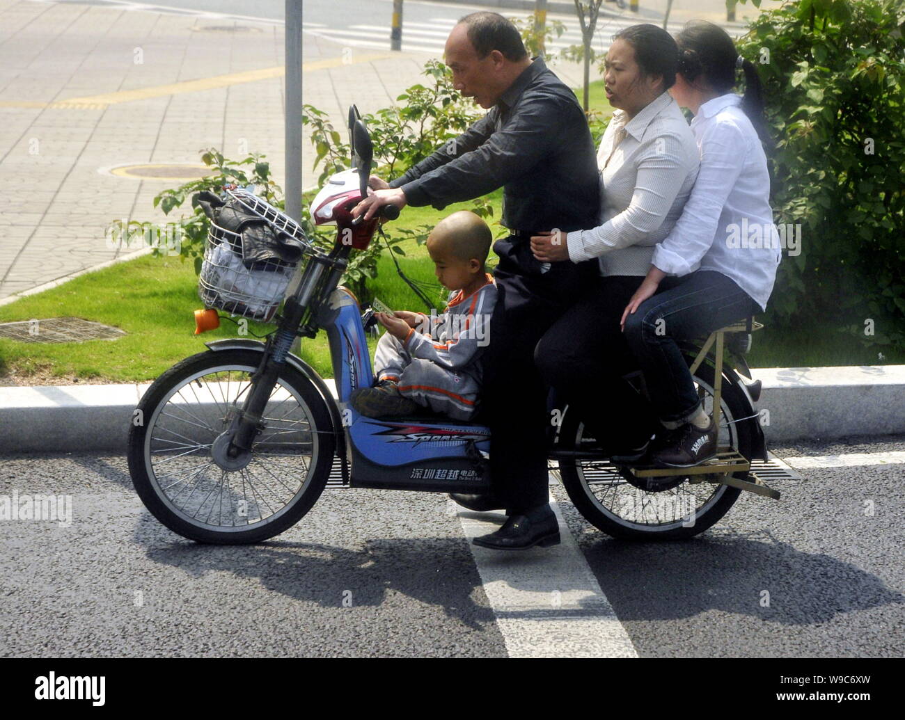 --FILE--A Chinese man rides his electric bicycles carrying his family ...