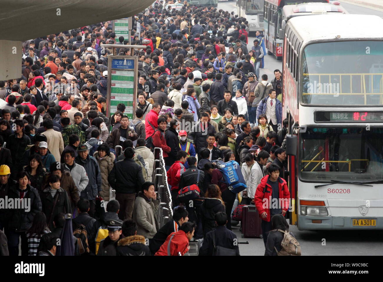 Chinese migrant workers crowd a bus stop at the Beijing West Railway ...