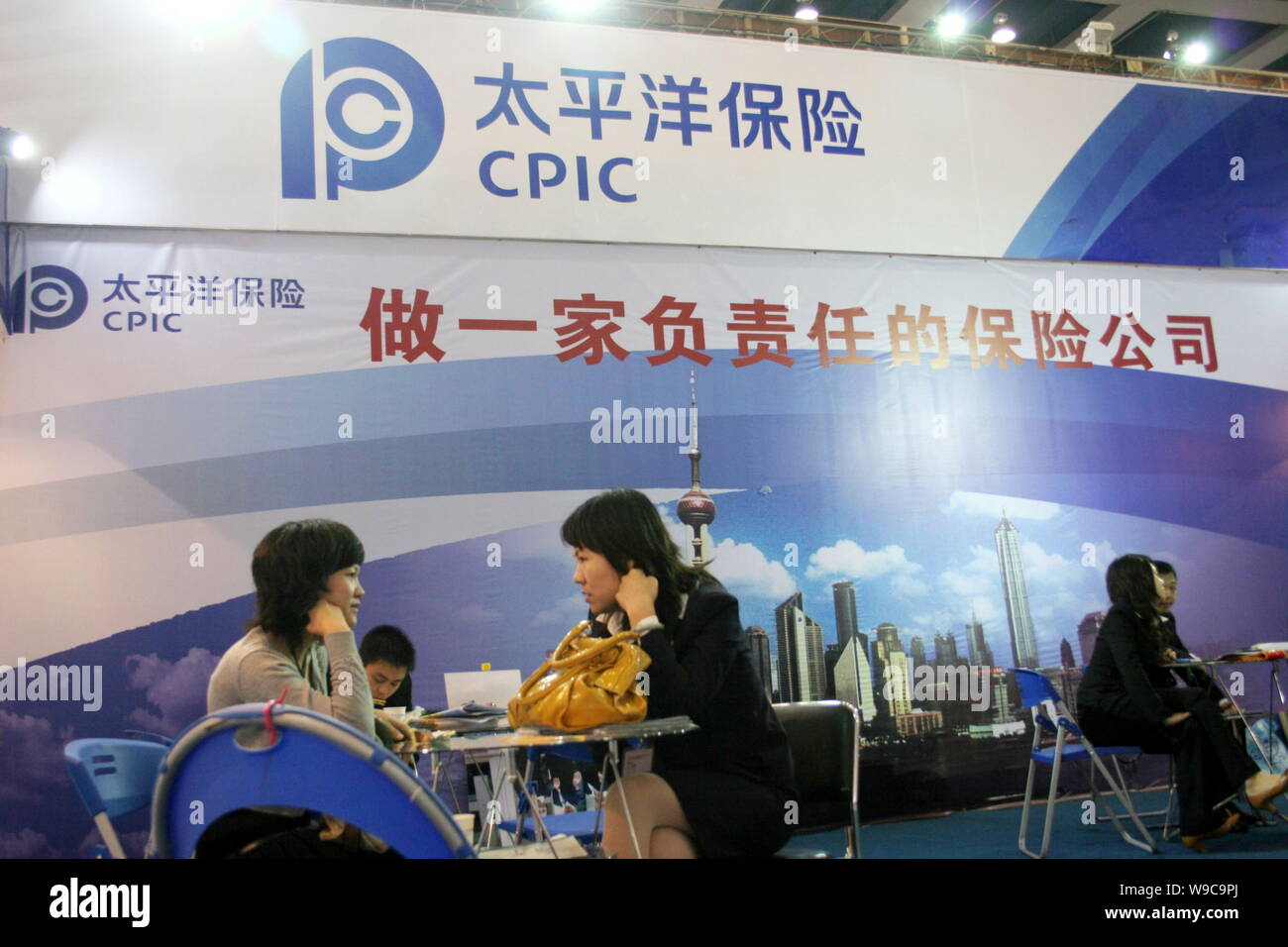 --FILE--Chinese staff talk with visitors at the stand of CPIC (China ...