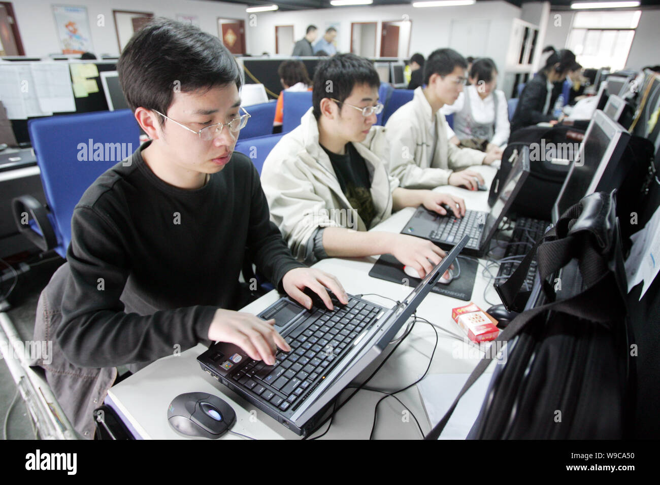 Chinese IT engineers work on their laptop computers at a cartoon ...