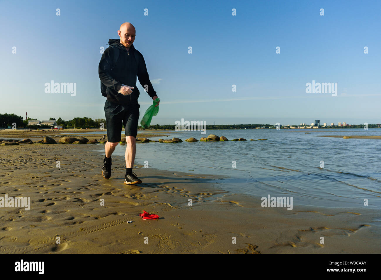 Man picking garbage on beach. At jogging or running. Plogging concept ...