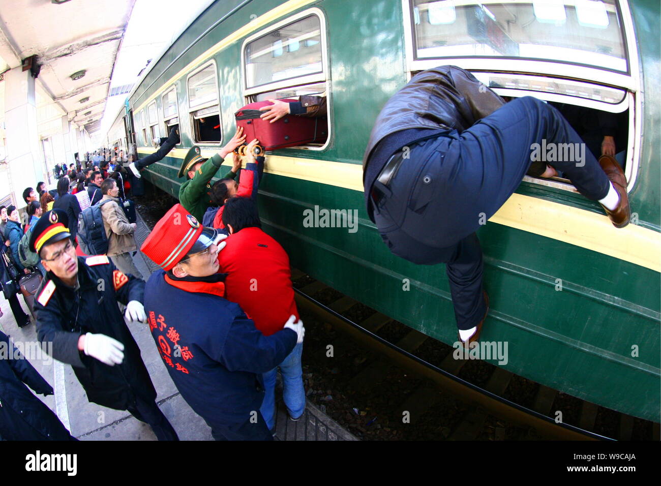 Chinese passengers climb into a train at Wuxi Railway Station in Wuxi ...