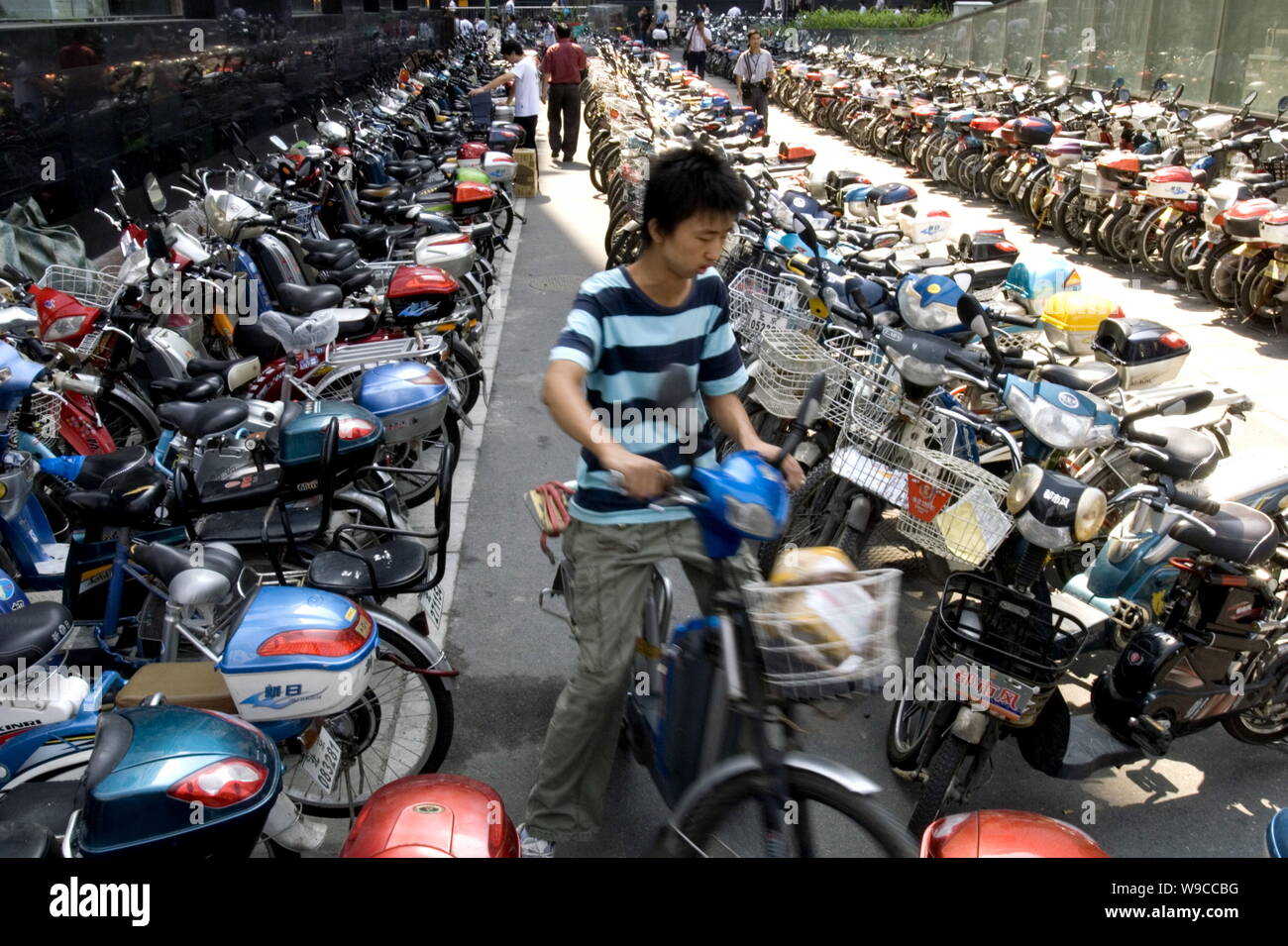 --FILE--A Chinese cyclist rides his electric bicycle amid rows of ...