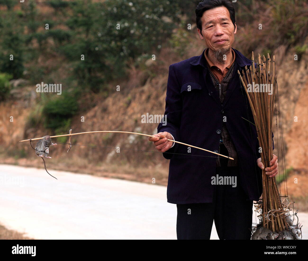 A Chinese farmer of Dong ethnic minority group shows a mouce trapped by ...