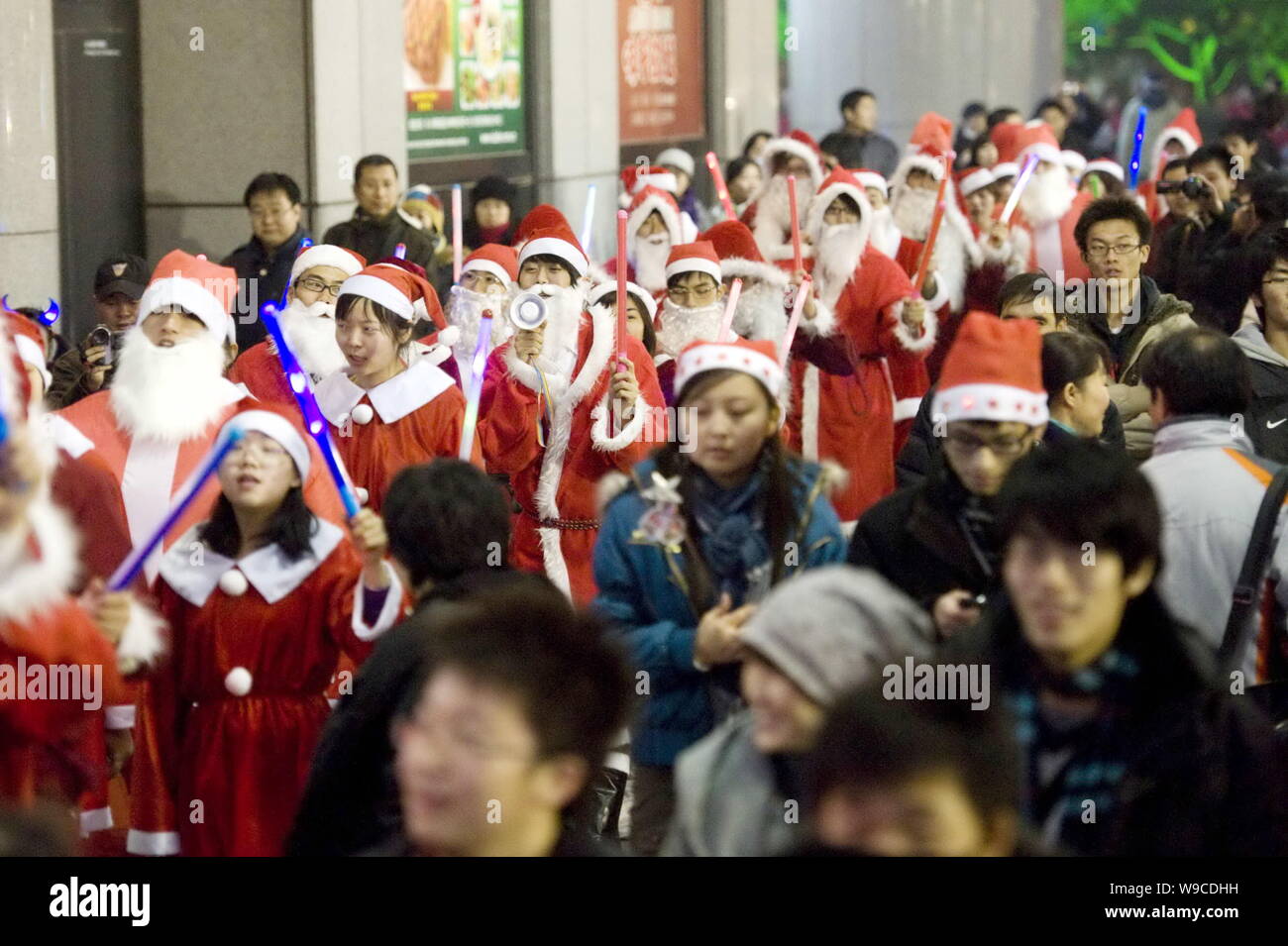 Chinese Santa Clauses celebrate on a shopping street on Christmas Eve ...