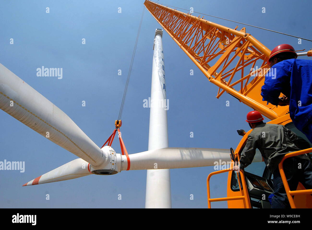Chinese workers assemble a wind power generation turbine at a wind farm ...