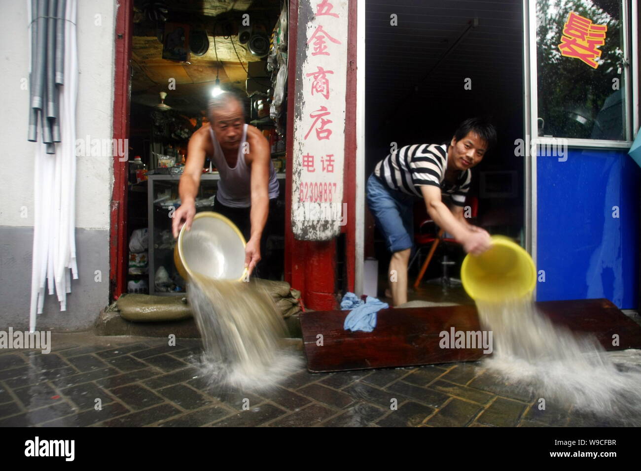 Local Chinese citizens pour water out from their houses after heavy ...