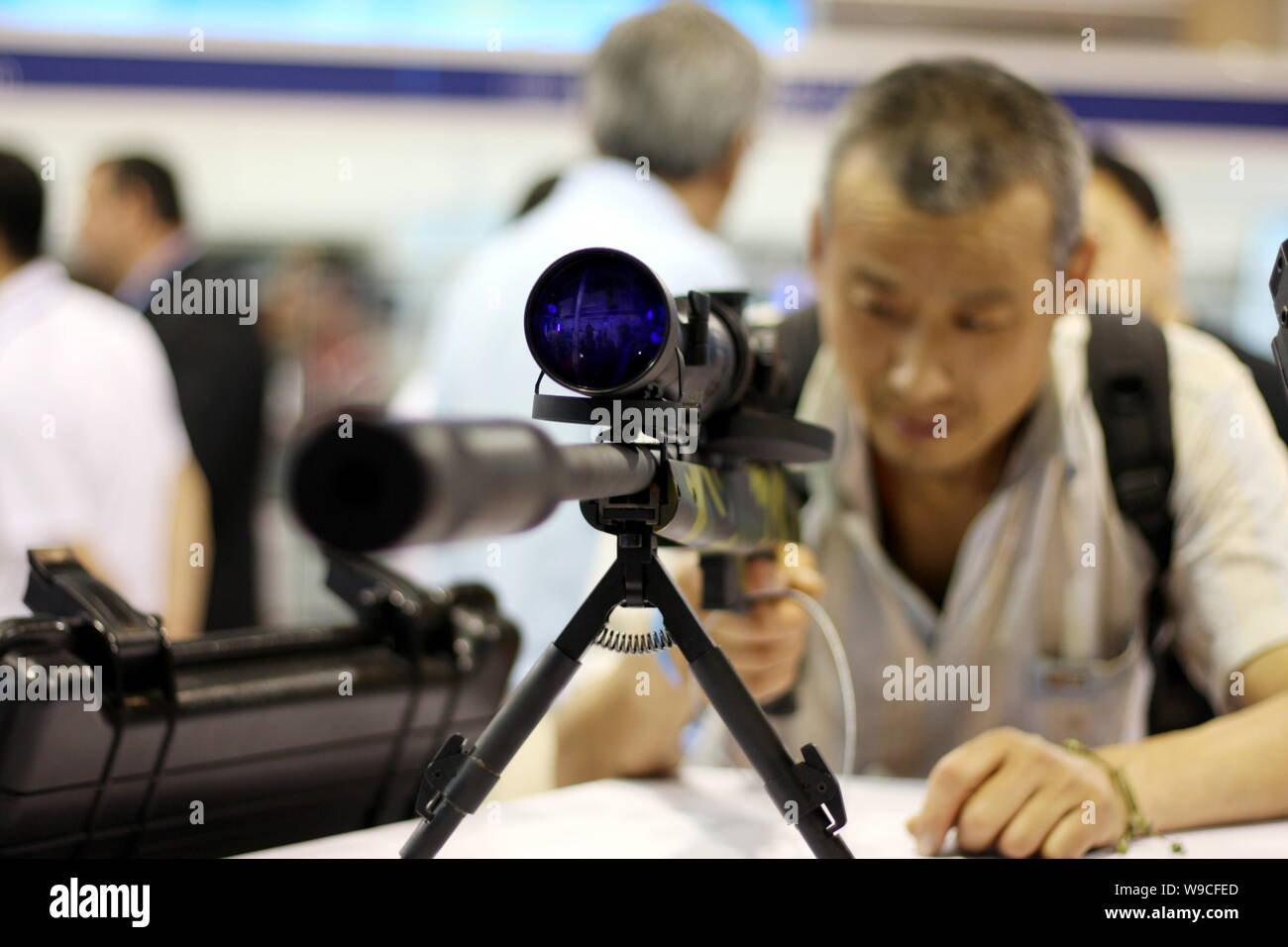 A visitor tries a sniper rifle on display at the 3rd China (Beijing ...