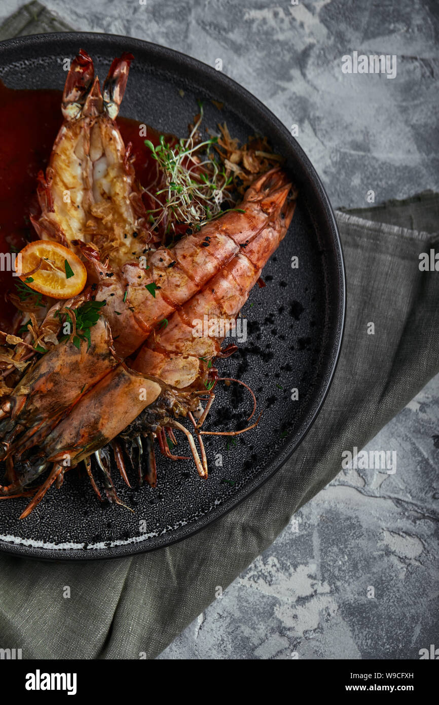 Grilled king prawns, with tomato sauce on a gray background, low key ...