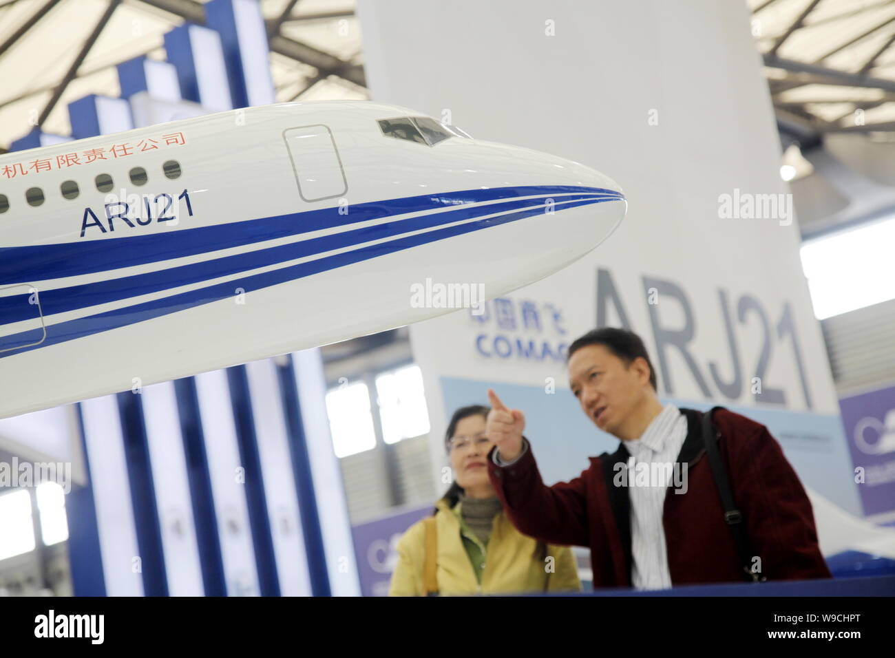 Visitors look at a model ARJ21 jet plane on display at the stand of ...