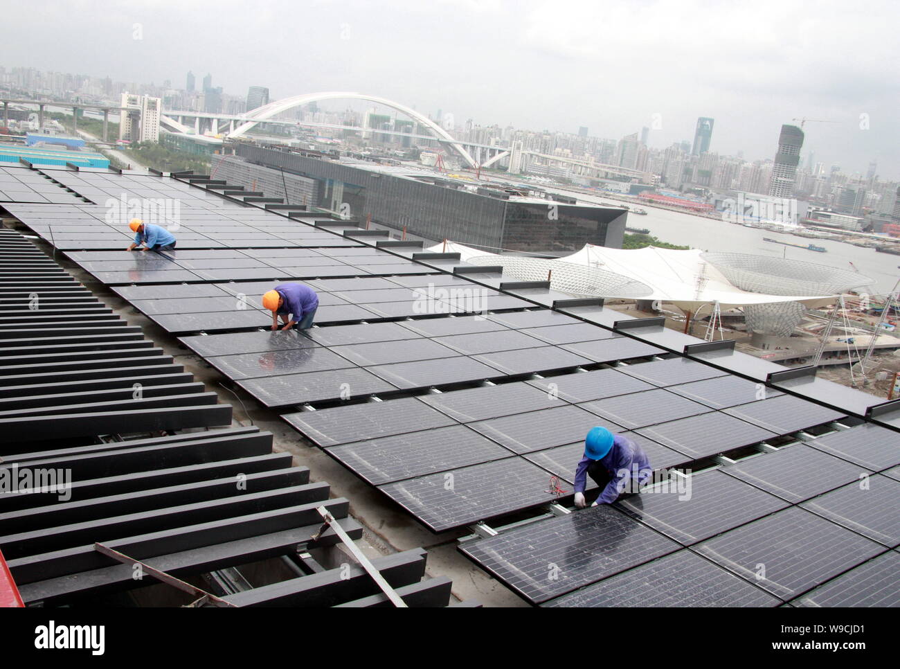 Chinese workers install solar panels on the rooftop of the China ...