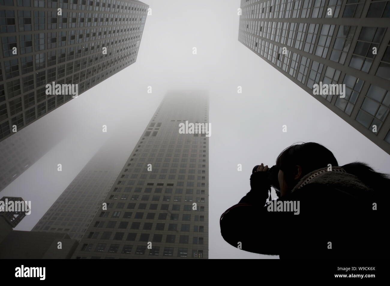 A Chinese woman takes pictures of the Yintai Centre complex amid a hazy ...