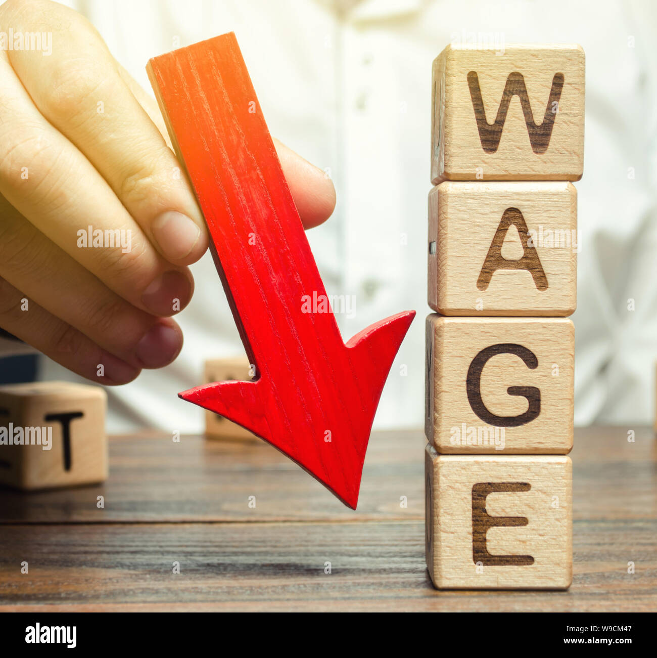 Wooden blocks with the word Wage and red arrow down. Salary reduction ...
