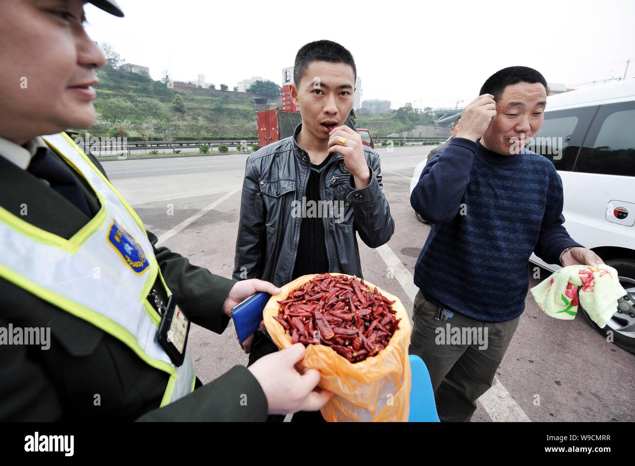 A Chinese police officer offers hot chili peppers to drivers at a ...