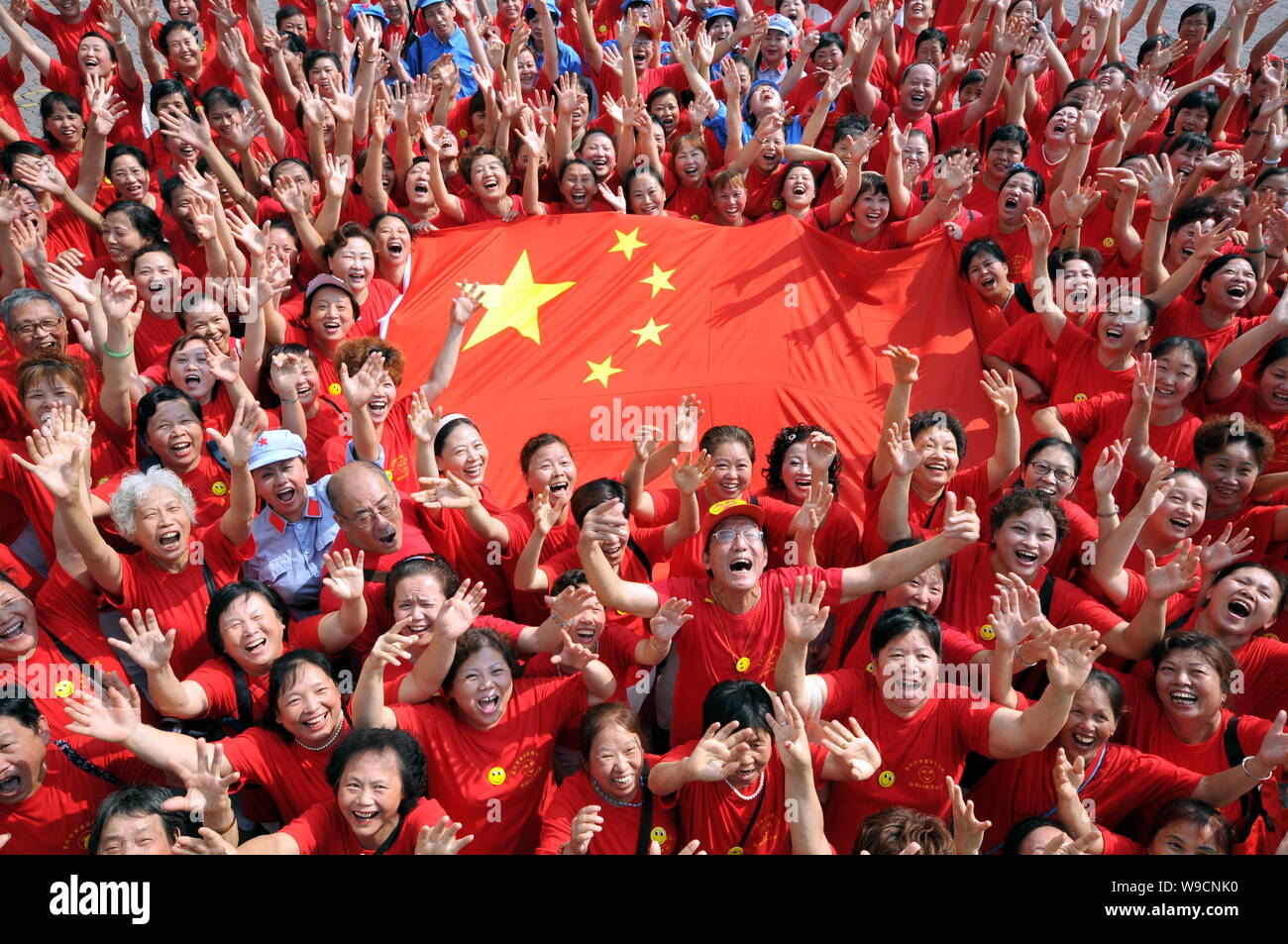 Local Chinese citizens surrounding the Chinese national flag laugh ...