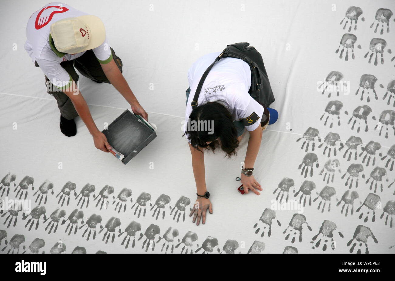 A young Chinese woman leaves her handprint on a huge handprint painting ...