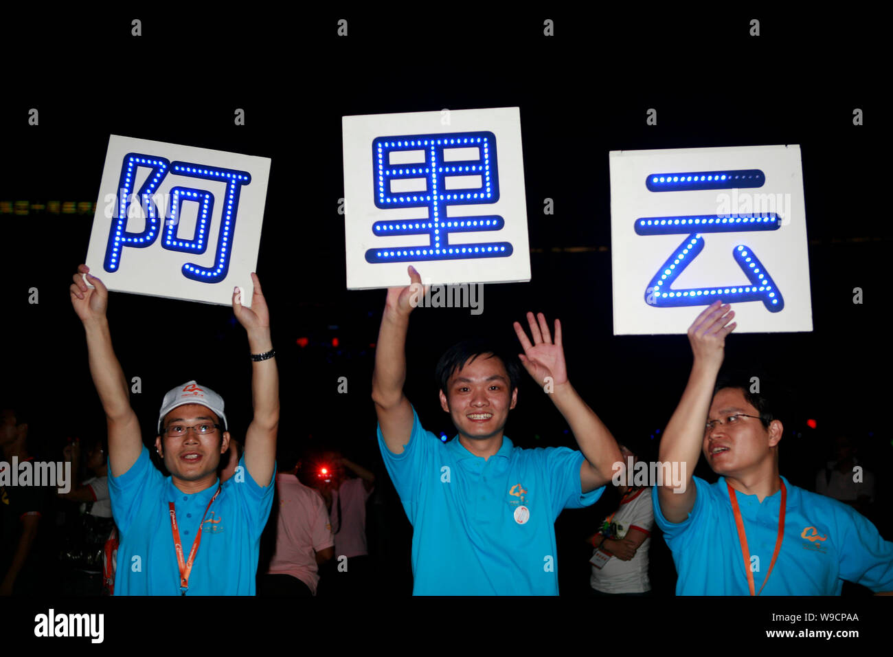 Three Alibaba employees hold boards with Chinese characters on, which ...