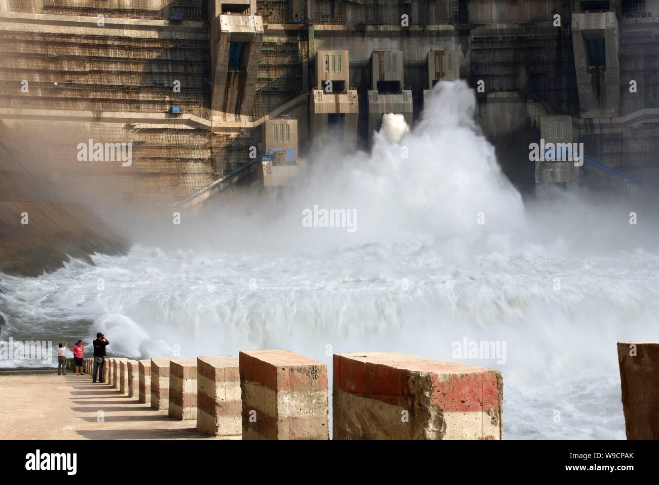 People look at water being discharged from the dam of the Xiaowan ...
