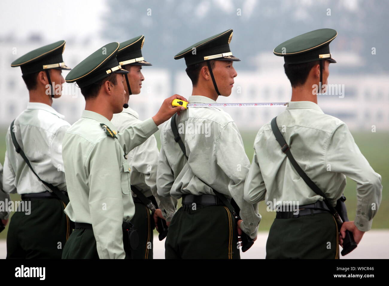 A Chinese paramilitary policeman, front, measures the heights of ...