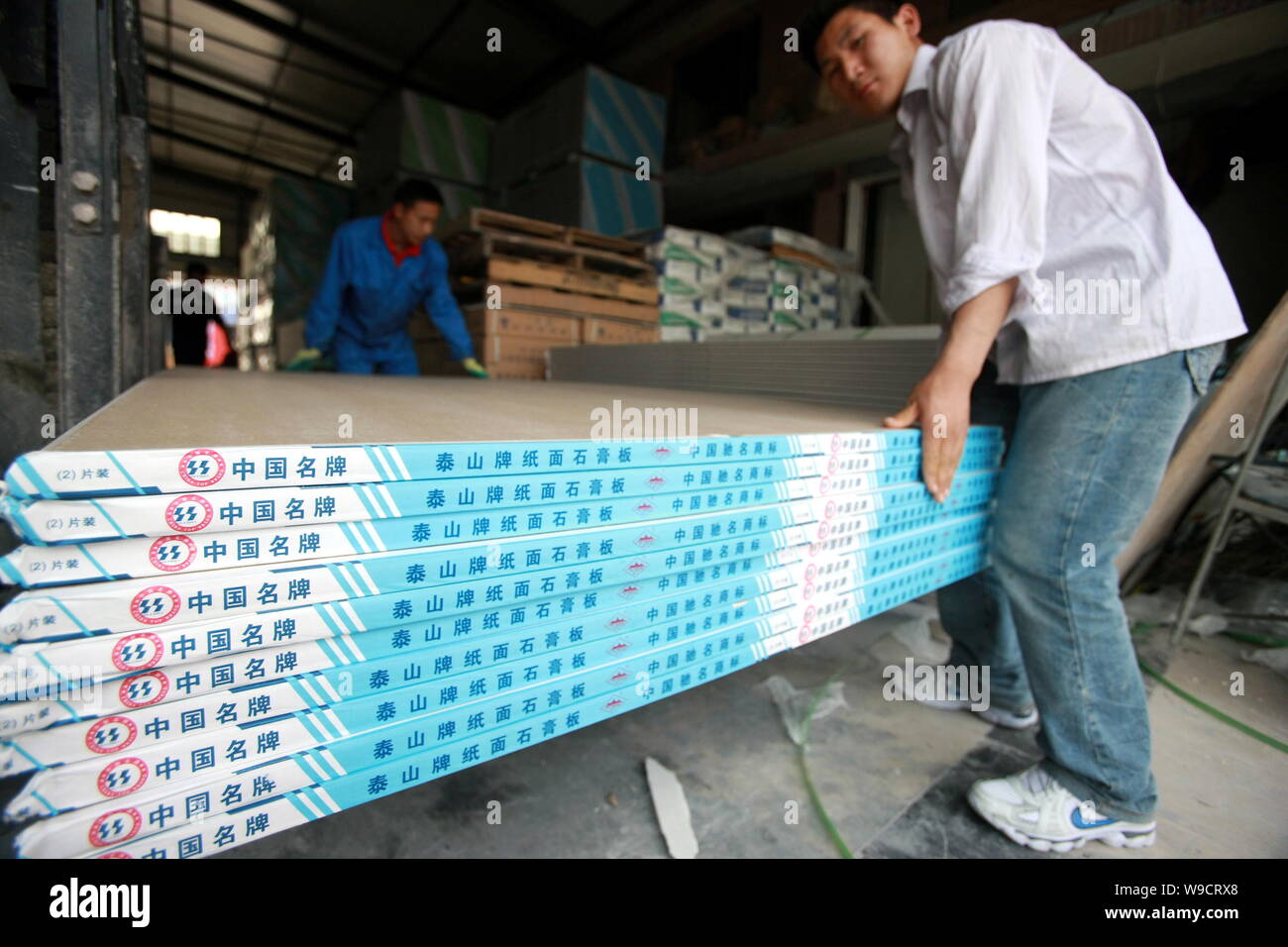 Chinese workers load a forklift with plasterboards a construction ...